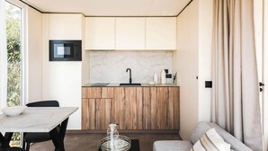 Uma cozinha compacta com painel de parede de mármore, armários de madeira e micro-ondas preto.