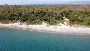 Vista aérea de uma praia com águas turquesa cristalinas, areal arenoso e vegetação densa.