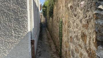 Uma passagem estreita com uma parede de pedra de um lado e um edifício branco do outro.