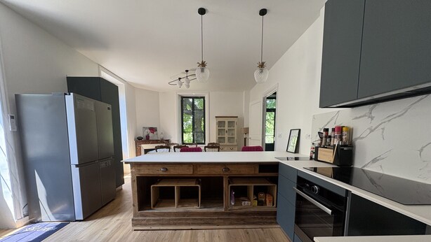 Uma cozinha moderna com uma ilha grande, eletrodomésticos embutidos e vista para a sala de jantar.