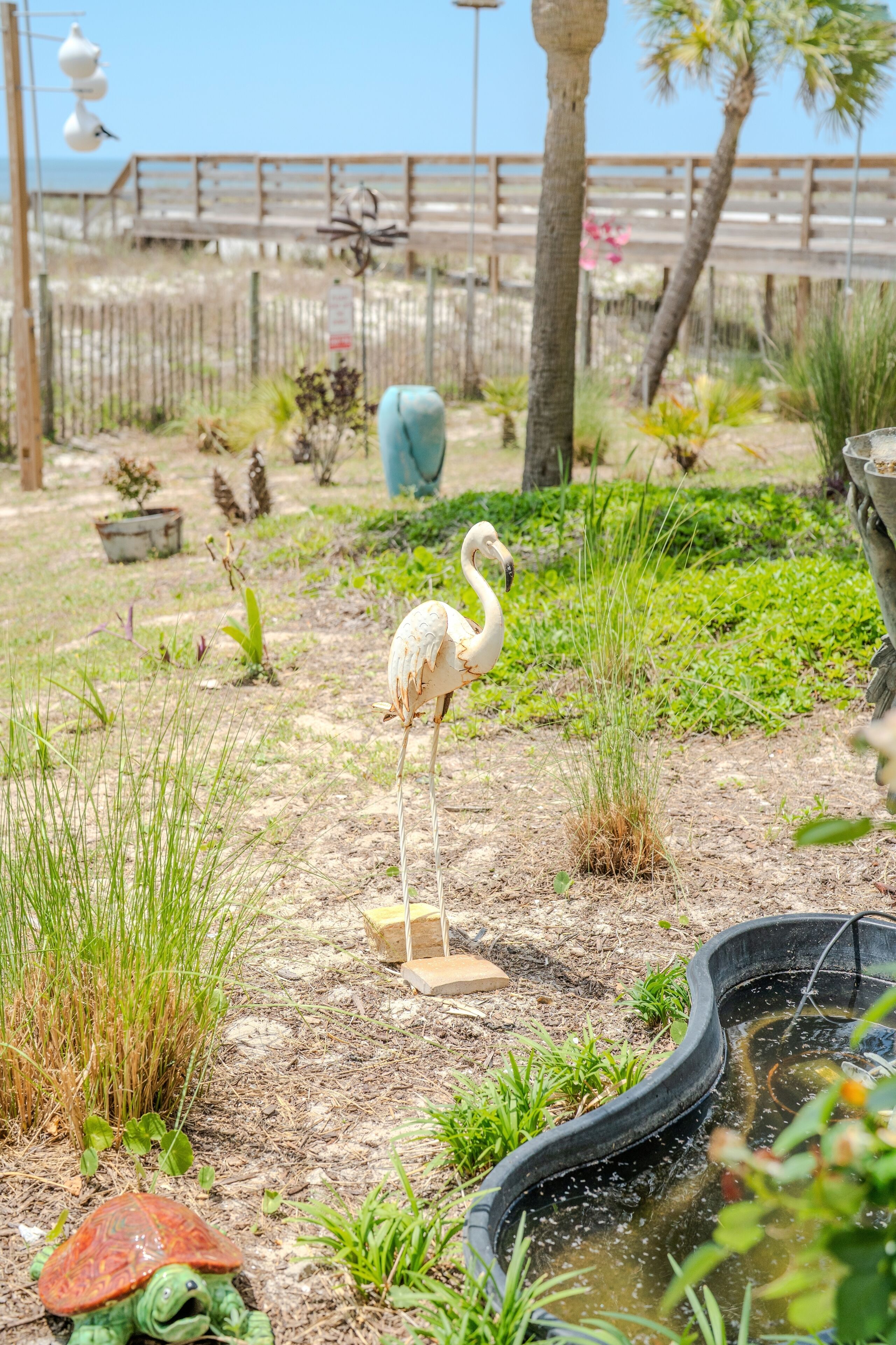 Um banho de pássaros, uma tartaruga e um flamingo em um jardim bem cuidado.