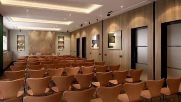 Uma sala de conferências com fileiras de cadeiras, uma parede de madeira com obras de arte emolduradas e um design moderno no teto.
