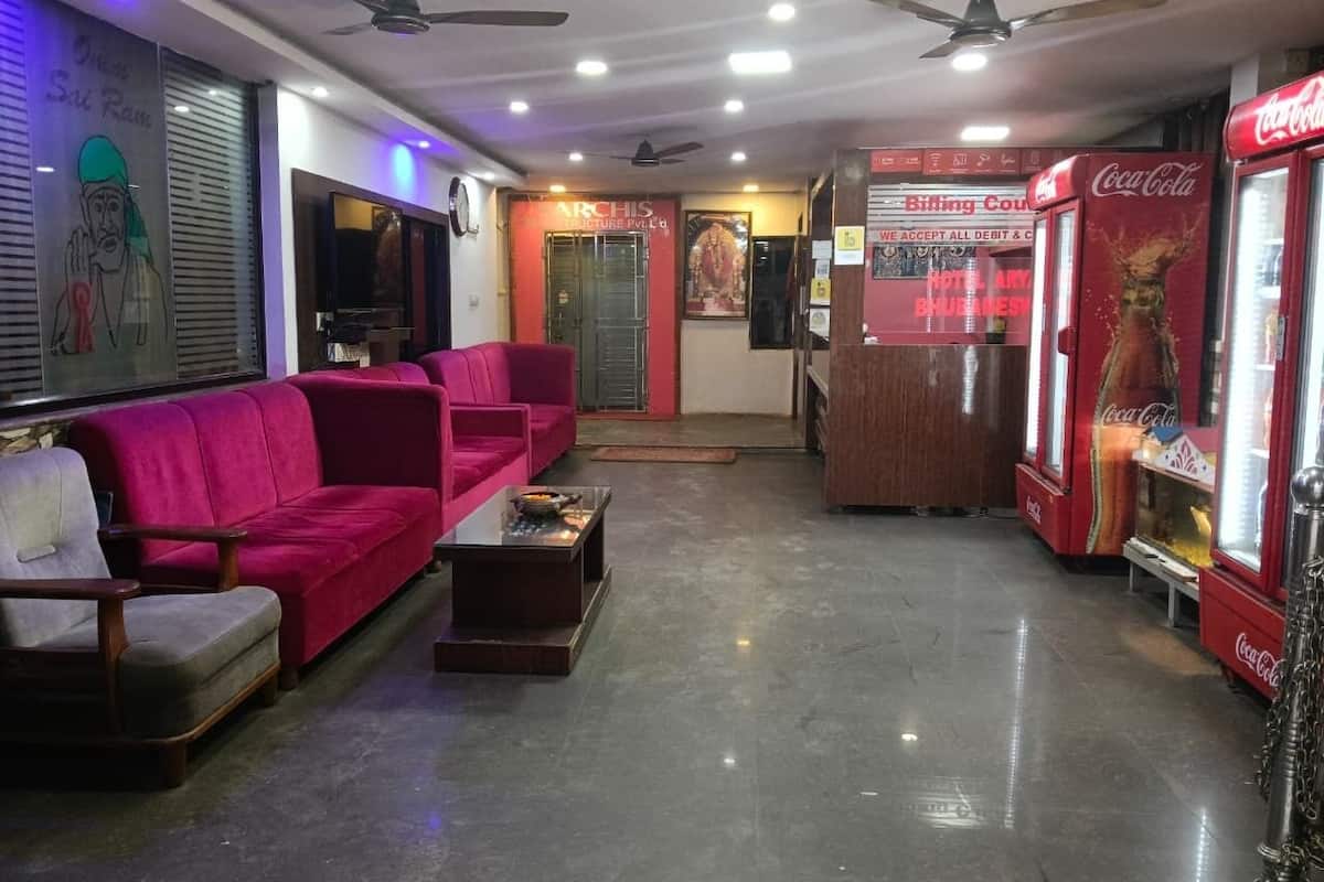 Um hall de hotel com assentos, uma máquina de venda automática de Coca-Cola e uma área de recepção.