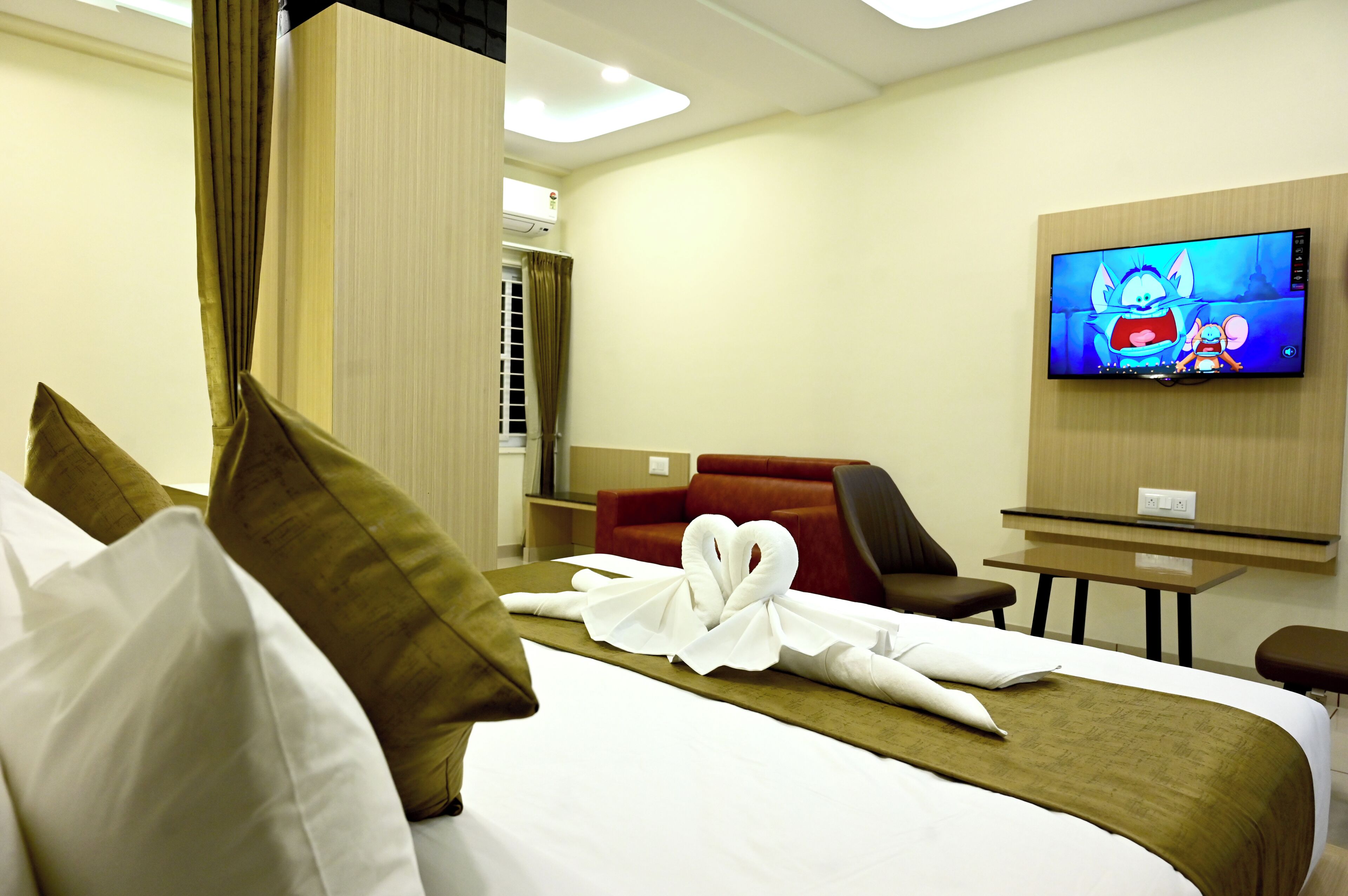 Quarto de hotel com cama, televisão, escrivaninha e sofá vermelho.