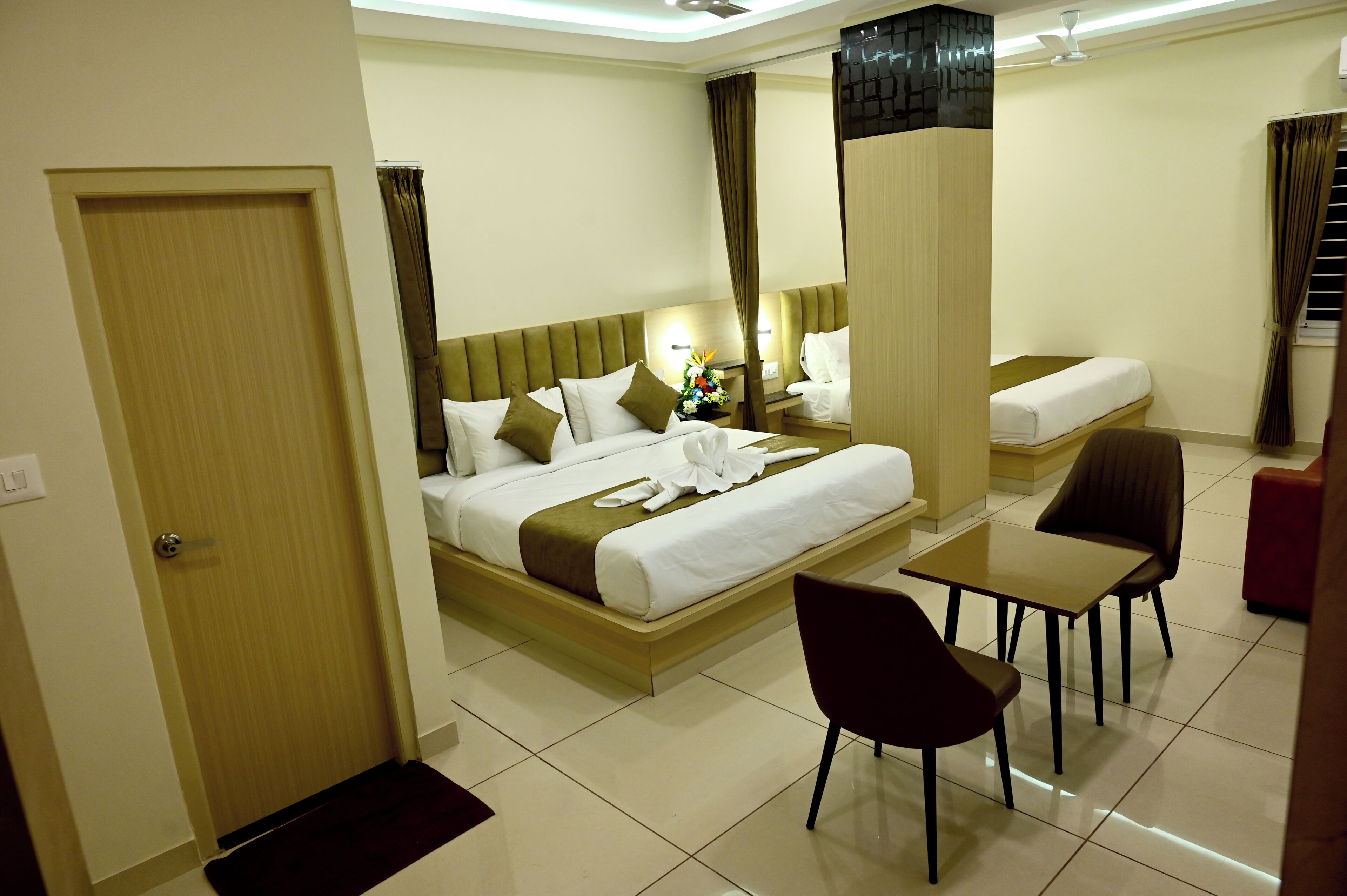 Quarto de hotel com cama, escrivaninha, cadeira e mesa pequena.