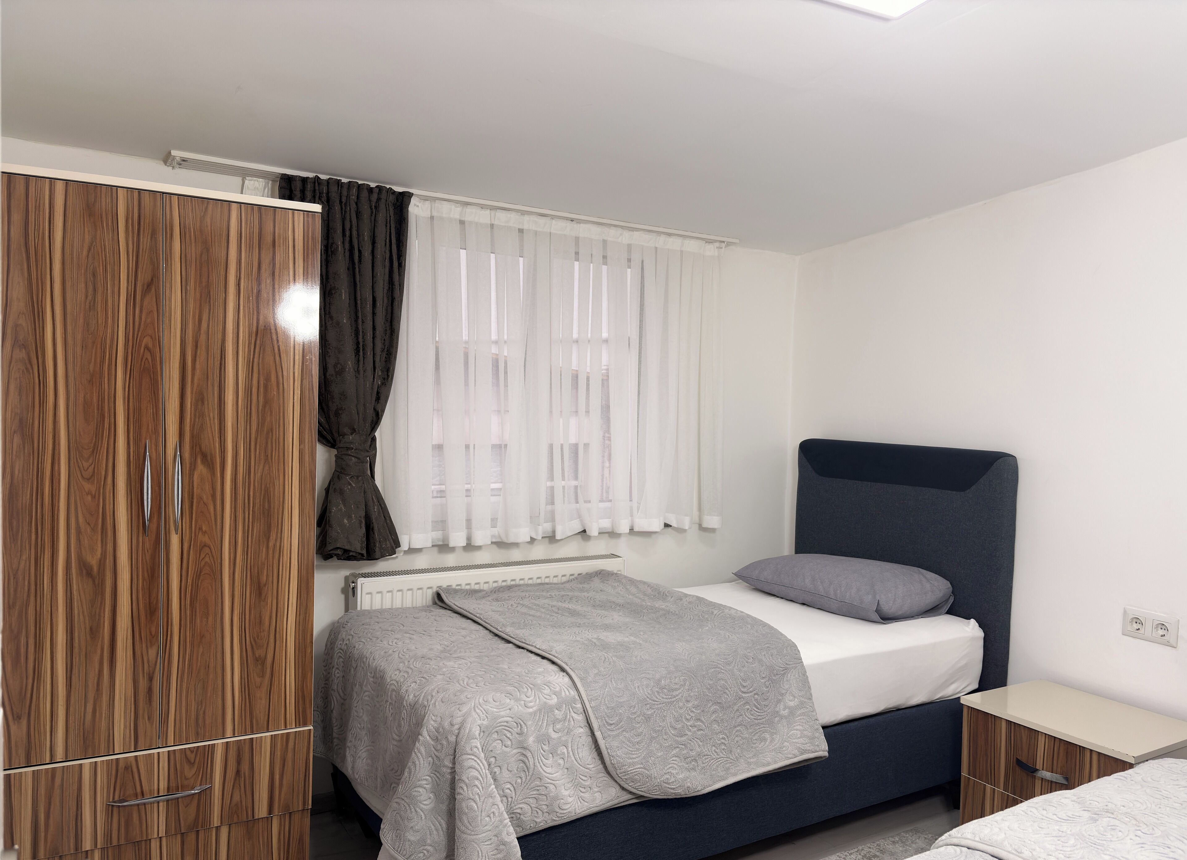 Um quarto com uma cama, um guarda-roupa e um radiador.