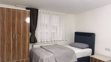 Um quarto com uma cama, um guarda-roupa e um radiador.