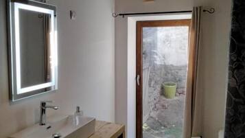 Um banheiro moderno com toucador de madeira, um espelho grande e um lustre suspenso.