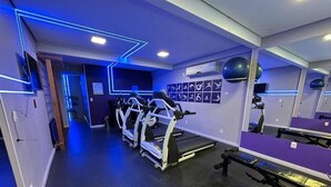 Uma academia com esteiras, elípticos e equipamentos de musculação.