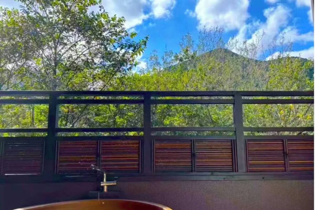 Uma banheira de madeira com vista para uma paisagem montanhosa através de uma cerca de madeira.