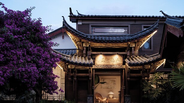 Um edifício tradicional com telhado de telhas, portas de madeira e uma placa com caracteres chineses.