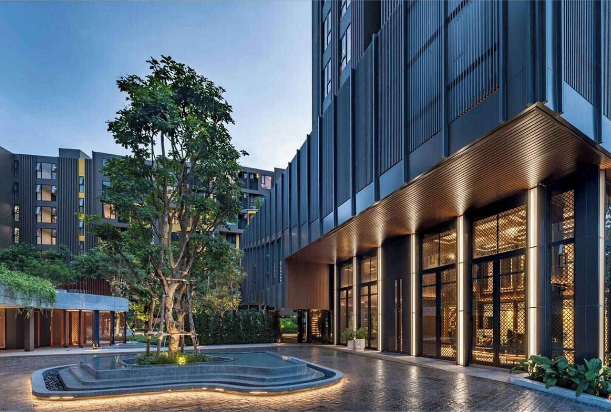 Um hotel moderno com um pátio, grandes janelas e uma entrada bem iluminada.
