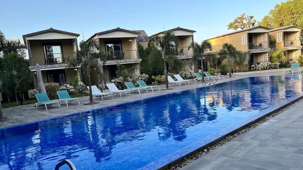 Piscina com espreguiçadeiras e um edifício com varandas.