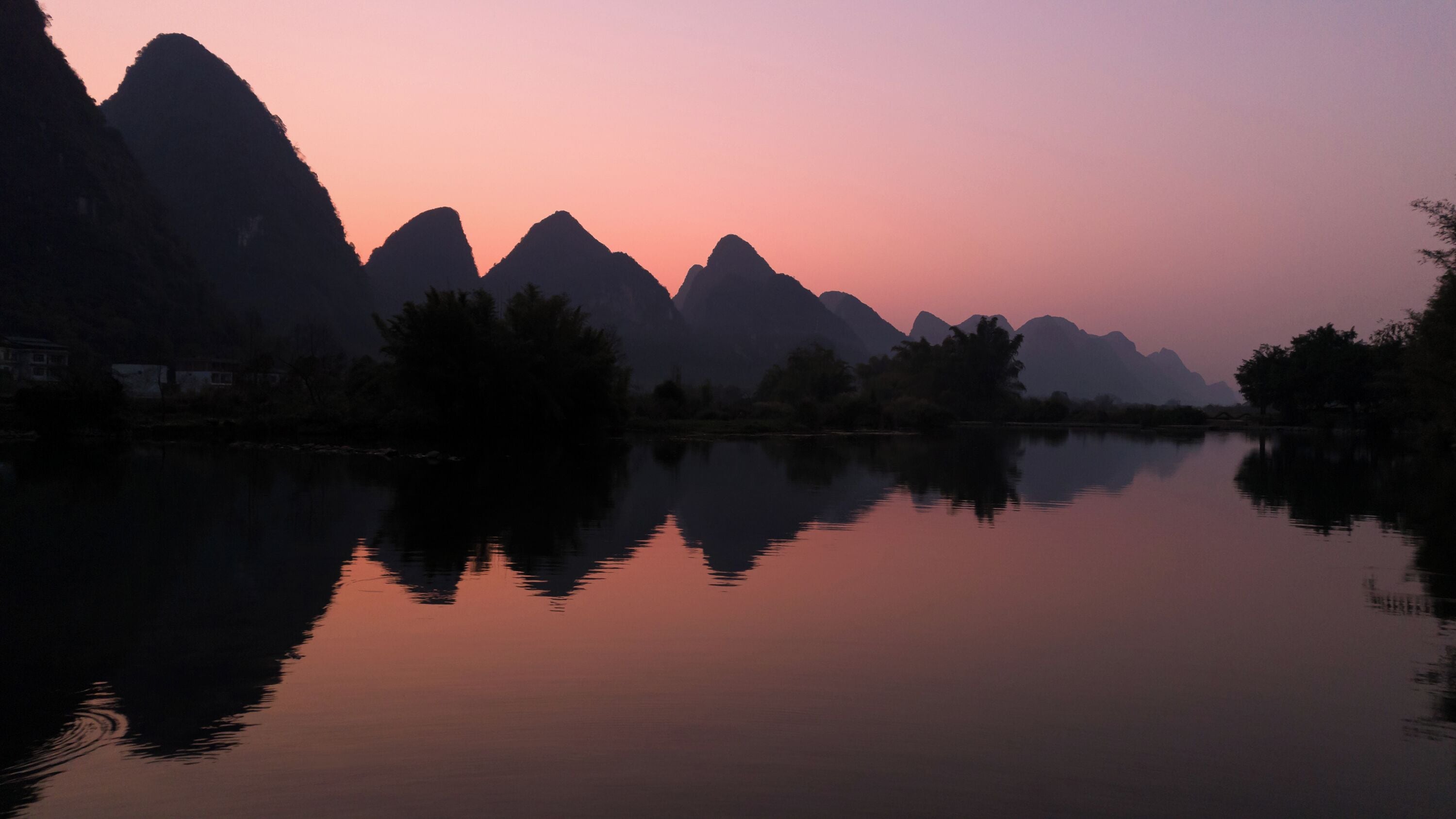 Um rio calmo refletindo montanhas ao pôr do sol.