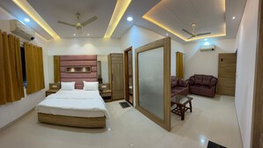Quarto de hotel moderno com uma cama grande, um sofá, um espelho e ventiladores de teto.