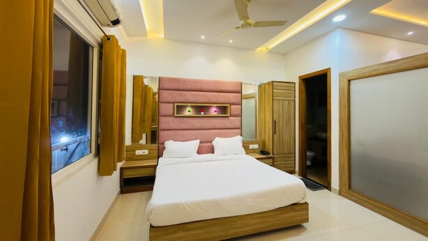 Quarto moderno com uma cama grande, uma penteadeira com espelho, um ventilador de teto e uma janela com cortinas.