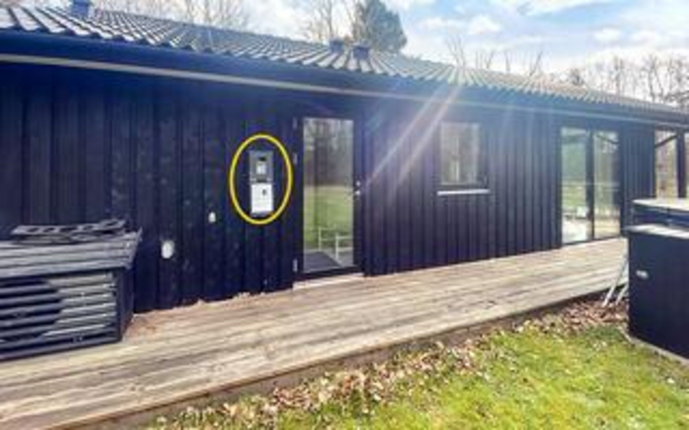 Um edifício moderno com um deck de madeira, uma porta com um sinal circular e uma janela.