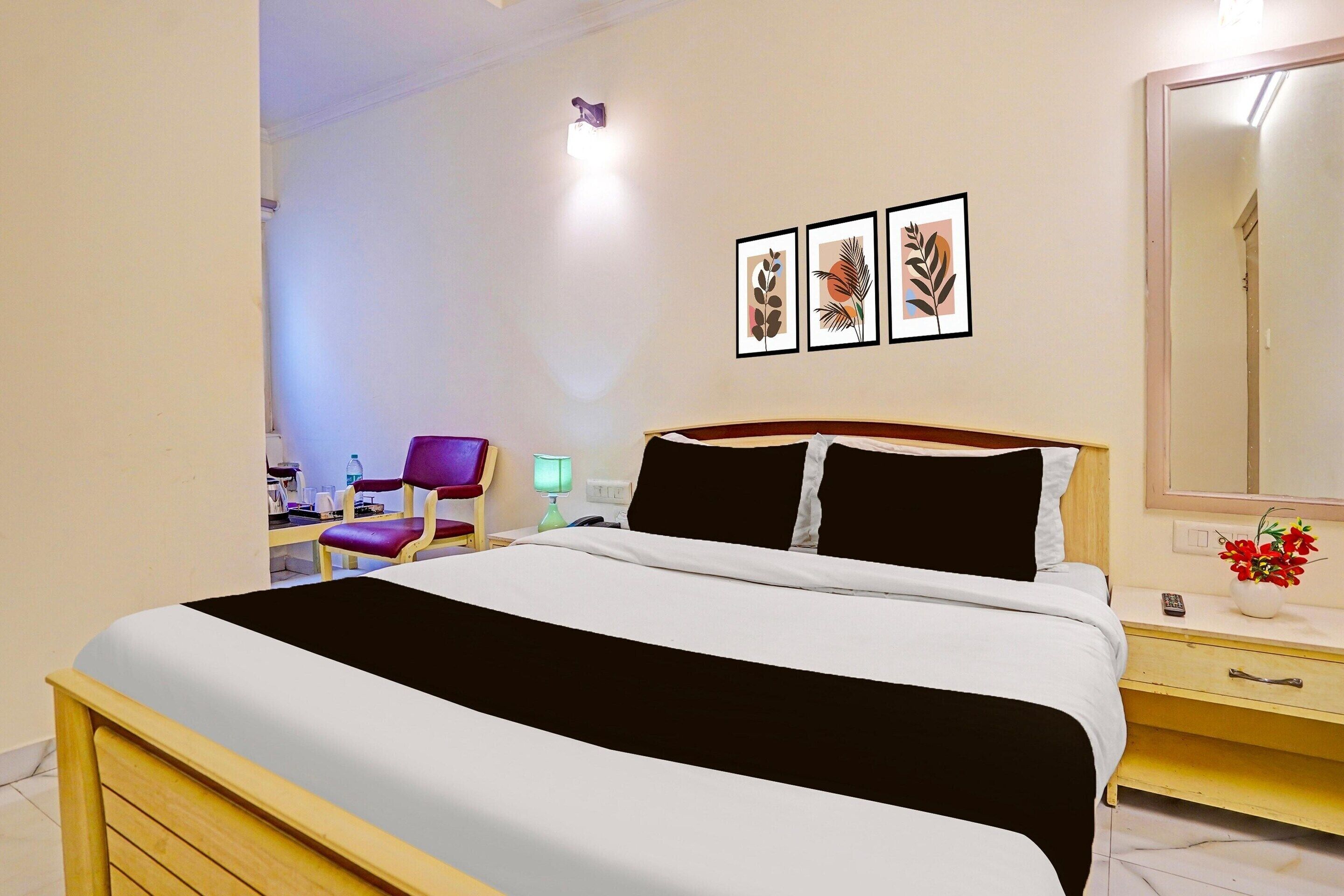 Quarto de hotel bem arrumado com uma cama grande, mesa de cabeceira, uma cadeira e um espelho.