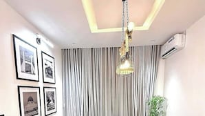 Uma sala de conferências moderna com uma mesa preta, cadeiras estofadas cinzas, um candelabro e quadros nas paredes.