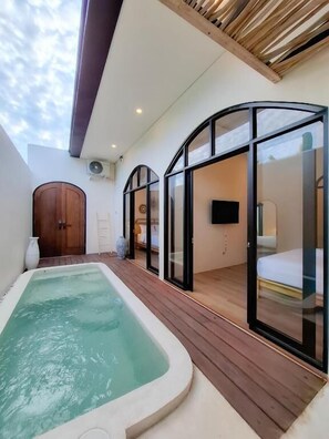 Uma área de spa moderna com hidromassagem, deck de madeira e salas com paredes de vidro.