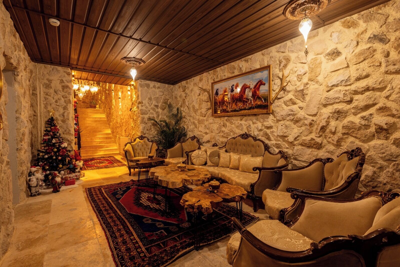 Um quarto aconchegante com parede de pedra, lareira, árvore de Natal e um conjunto de sofás.
