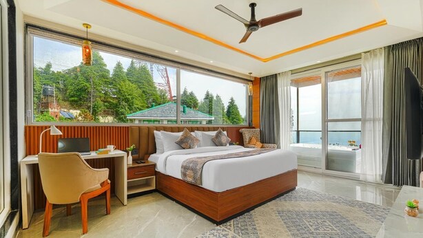 Quarto moderno com uma cama grande, uma escrivaninha e vista para o verde lá fora.