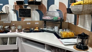 Um buffet de café da manhã com diversos alimentos e uma máquina de café.