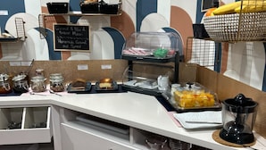 Um buffet de café da manhã com diversos alimentos e uma máquina de café.