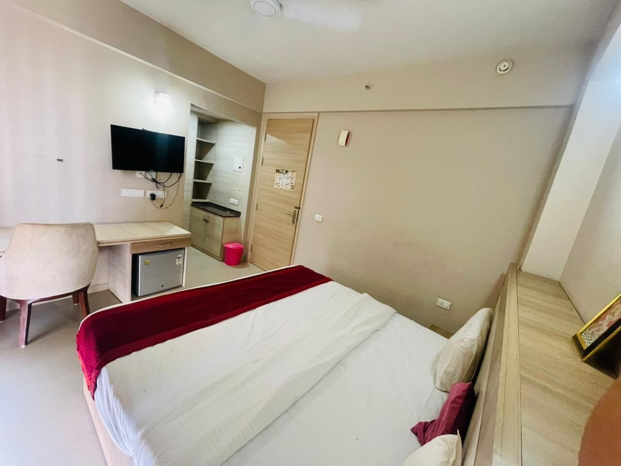 Quarto com cama, escrivaninha, cadeira, televisão e guarda-roupa.