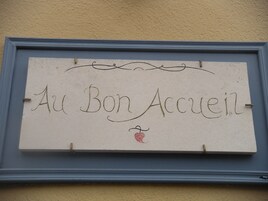 Um sinal com o texto 'Au Bon Accueil' e um pequeno símbolo de coração vermelho.