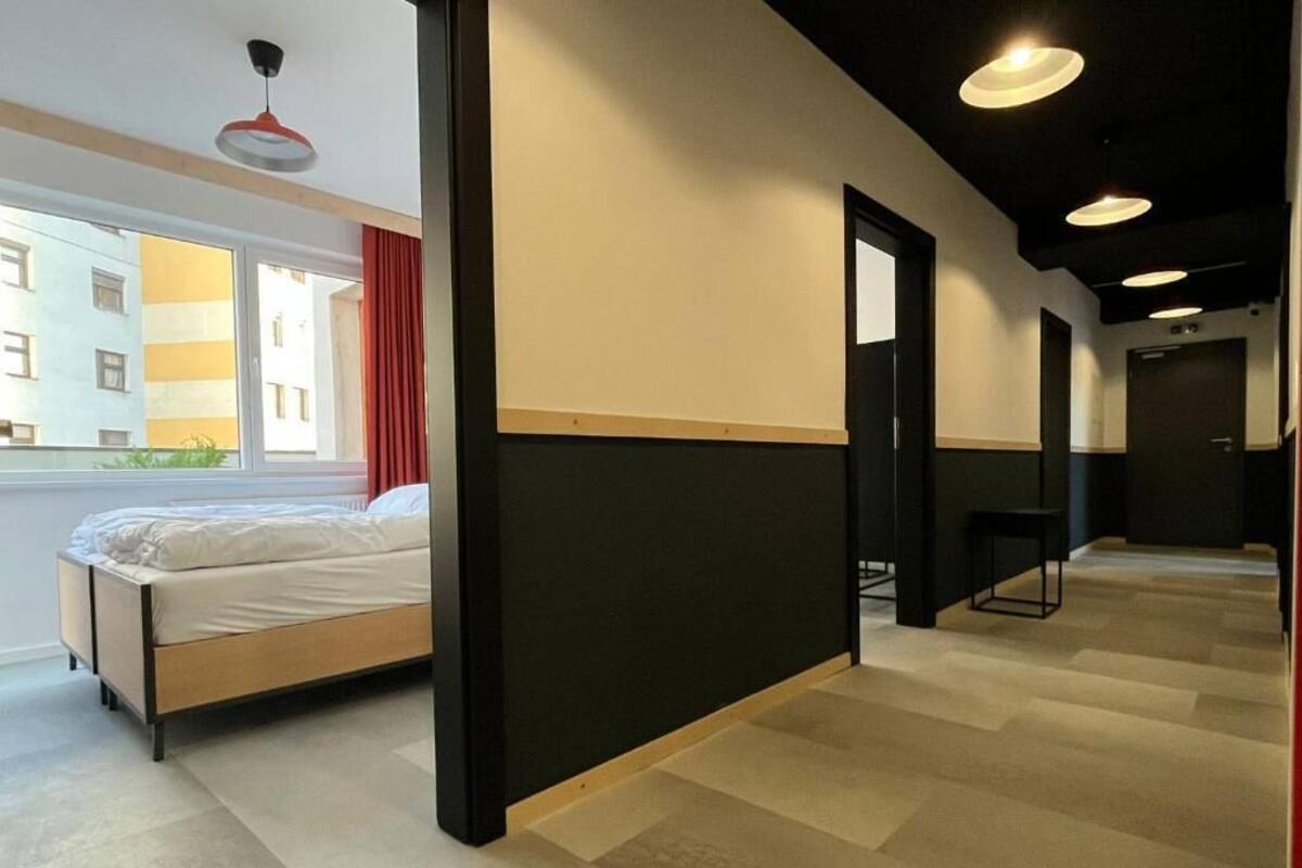 Quarto de hotel moderno com cama, uma janela grande e vista para um edifício.