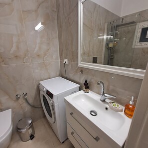 Casa de banho compacta com máquina de lavar roupa, lavatório e sanita.