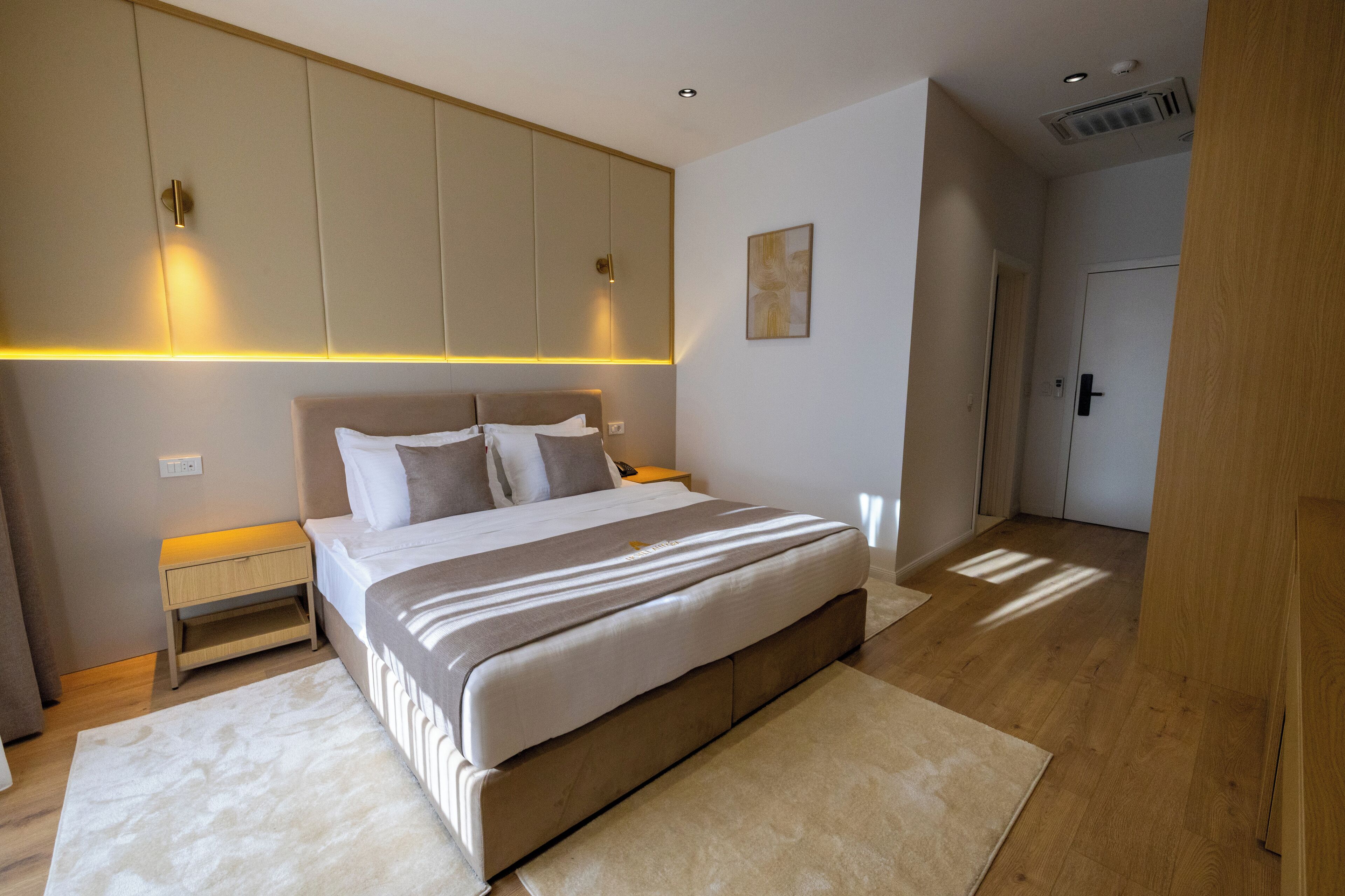 Quarto moderno com uma cama grande, mesas de cabeceira, um guarda-roupa e um quadro na parede.