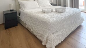 Quarto com cama, mesas de cabeceira, abajur, pintura e guarda-roupa.