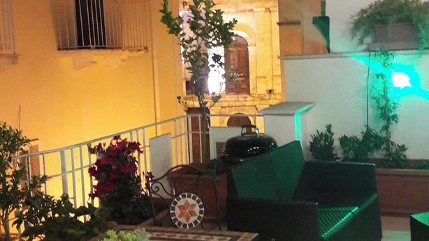 Uma área de pátio ao ar livre com mesa e cadeiras de azulejo e vasos de plantas.