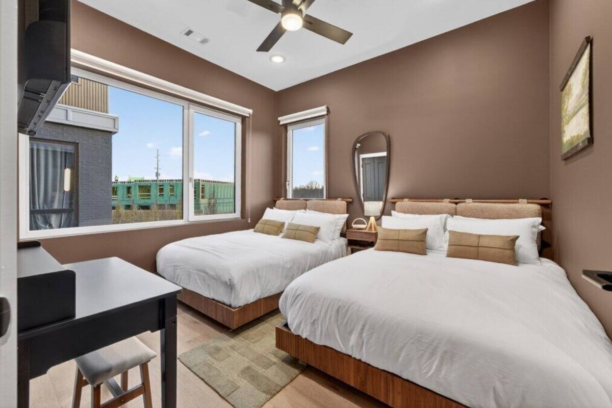 Quarto com duas camas, uma escrivaninha e um ventilador de teto.