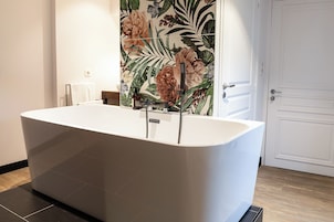 Um banheiro moderno com uma banheira independente, chuveiro e um painel decorativo com flores.