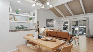 Uma sala ampla com uma mesa de jantar de madeira, um sofá e uma estante de livros.
