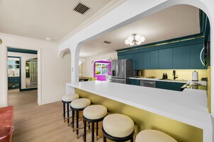 Uma cozinha moderna com uma ilha central, banquetas e armários cor de verde-água.
