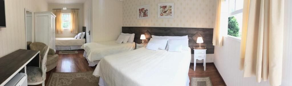 Quarto de hotel com duas camas, uma escrivaninha e uma cadeira.