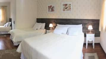 Quarto de hotel com duas camas, uma escrivaninha e uma cadeira.