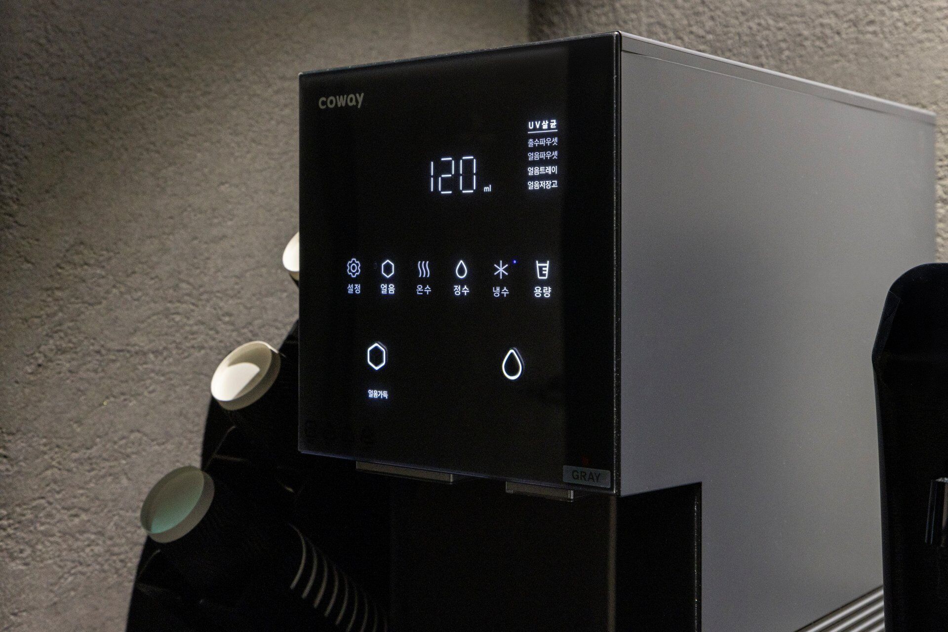 A black electronic device with a digital display reading "120 ml" and several control buttons.