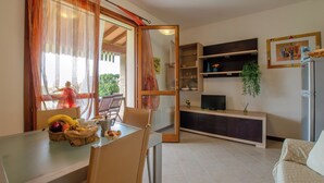 Uma sala de estar moderna com área de jantar, televisão e frigorífico.