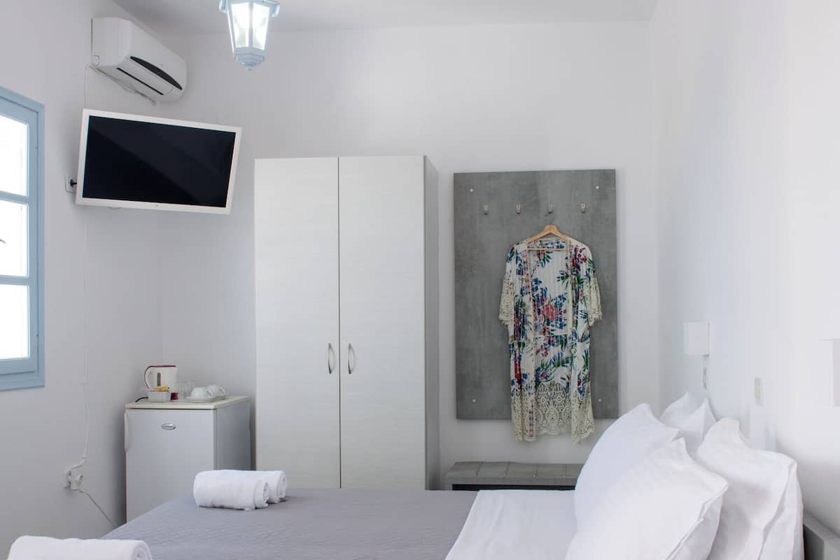 Um quarto moderno com cama, televisão, guarda-roupa e ar condicionado fixado na parede.
