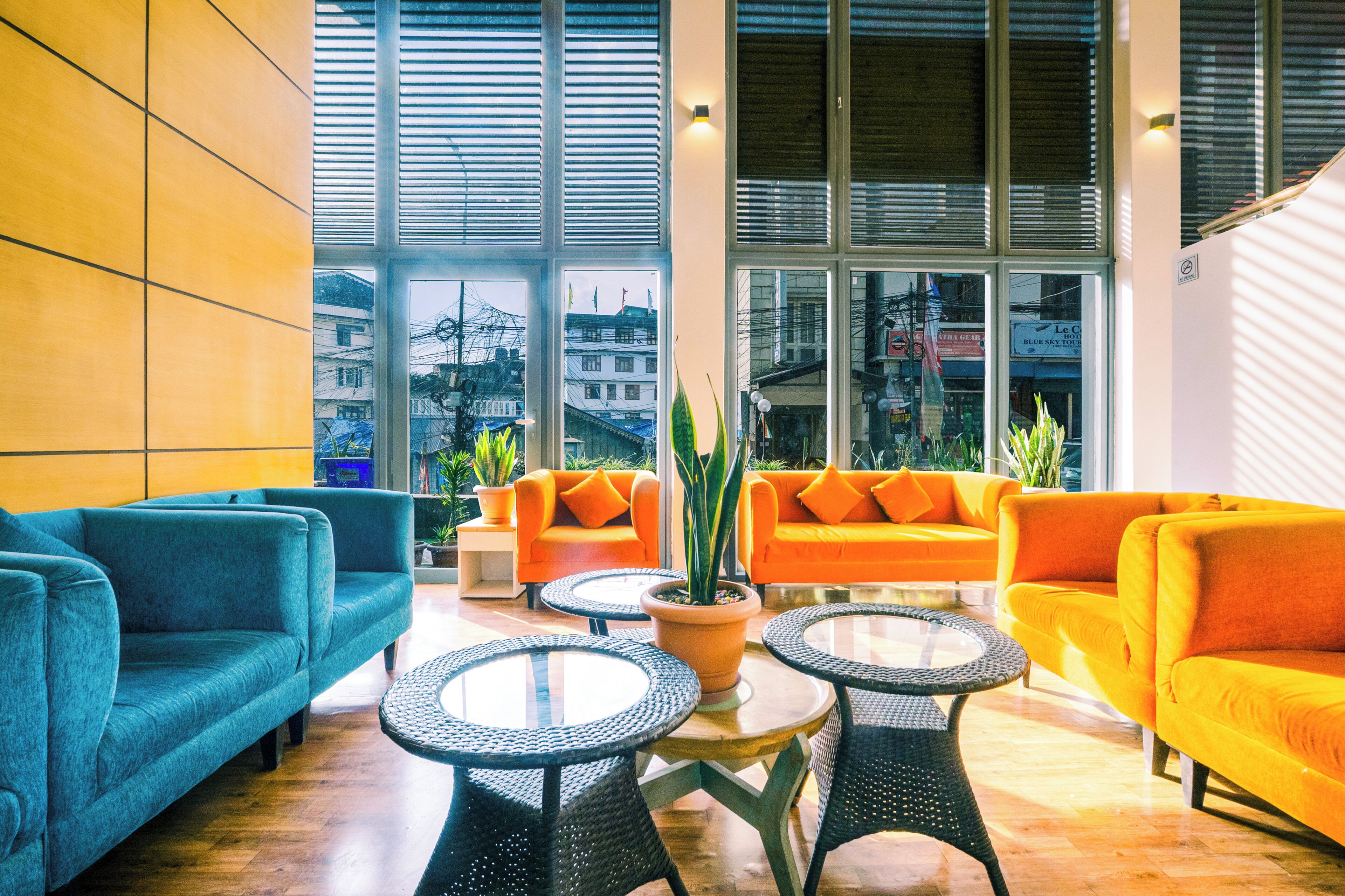 Um lobby moderno com um sofá azul, sofás laranja e mesas redondas.