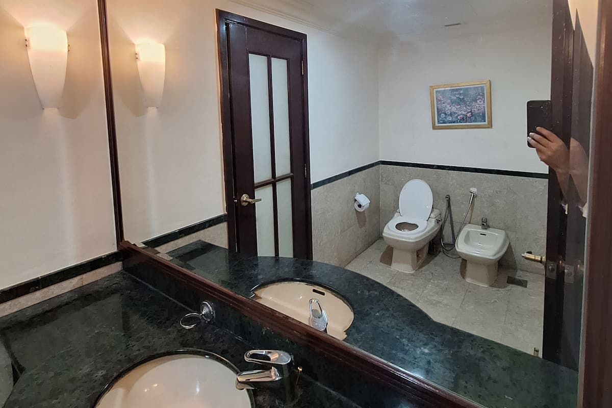 Casa de banho com um espelho grande, uma pia, uma sanita e um bidé.