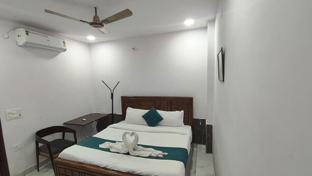Quarto com cama, escrivaninha, cadeira, ventoinha no teto e aparelho de ar condicionado.