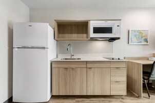 A compact kitchen with a built-in refrigerator, a microwave, and a sink.