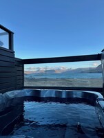 Uma banheira de hidromassagem com vista para montanhas e um corpo d'água.