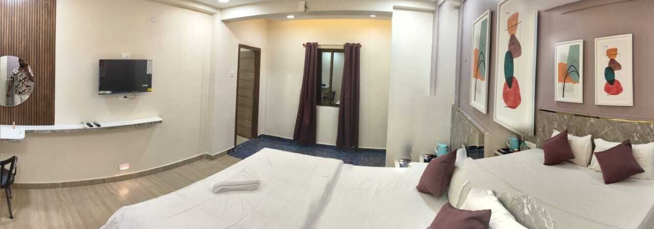 Quarto de hotel com cama grande, televisão, escrivaninha e banheiro.